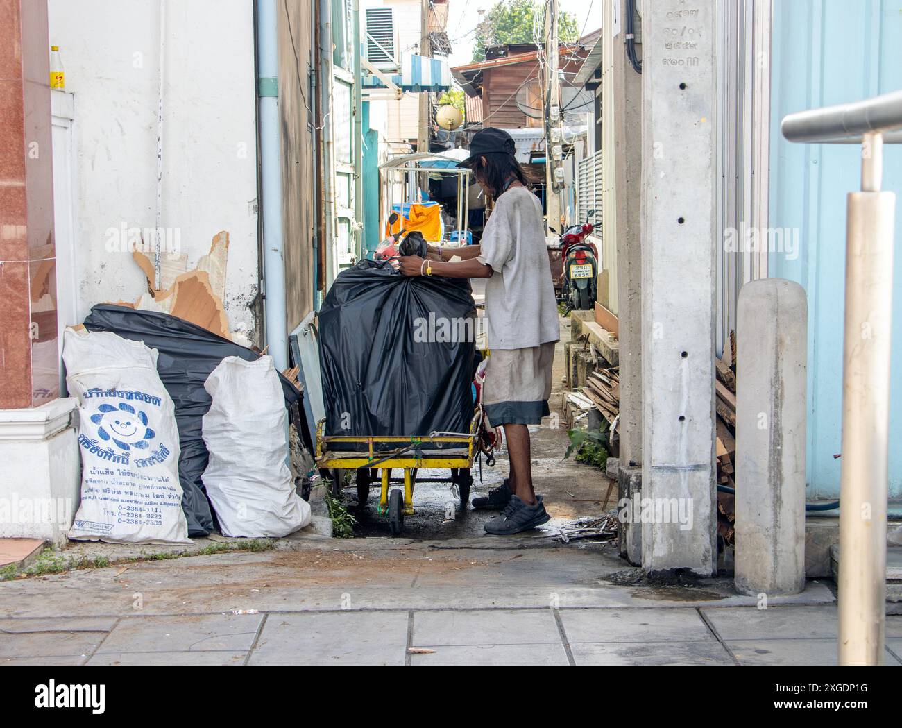 BANGKOK, THAILAND, JUNE 16 2024, A poor man is tying a big sack on a ...