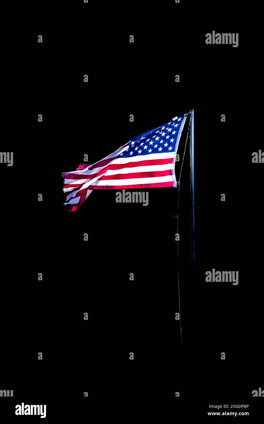 Ragged american flag on a pole in a black background with copy space ...