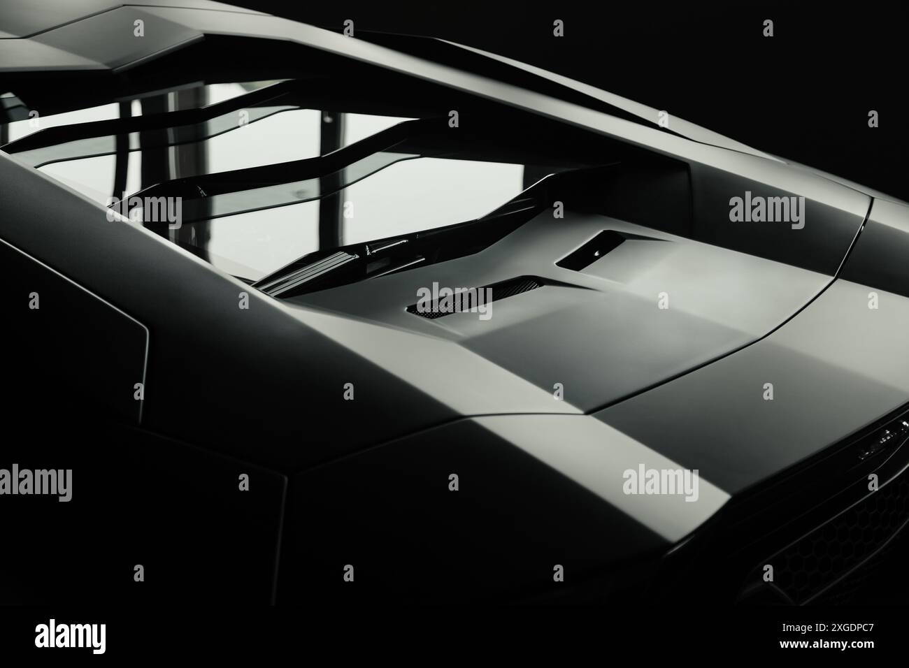 A sleek, modern sports car engine cover with a reflective glass surface ...