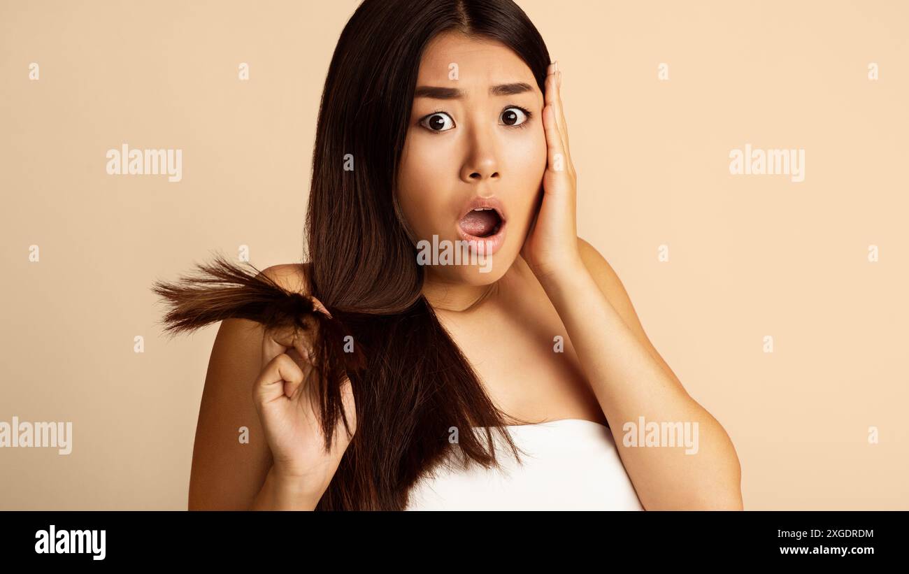 Woman Holding Damaged Hair Strand In Front Of Tan Background Stock ...