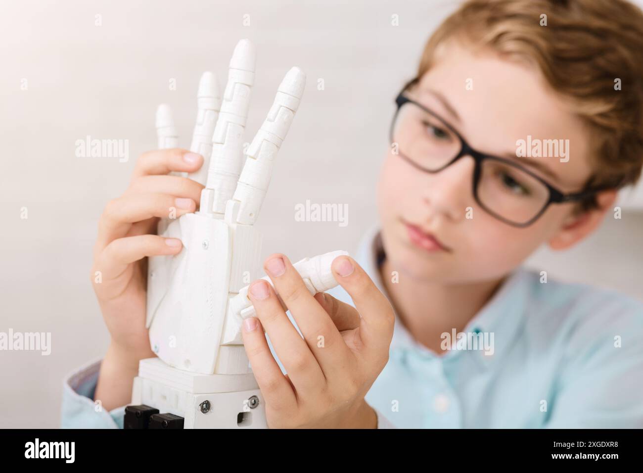 Young Boy Examining a White Robotic Hand Stock Photo - Alamy