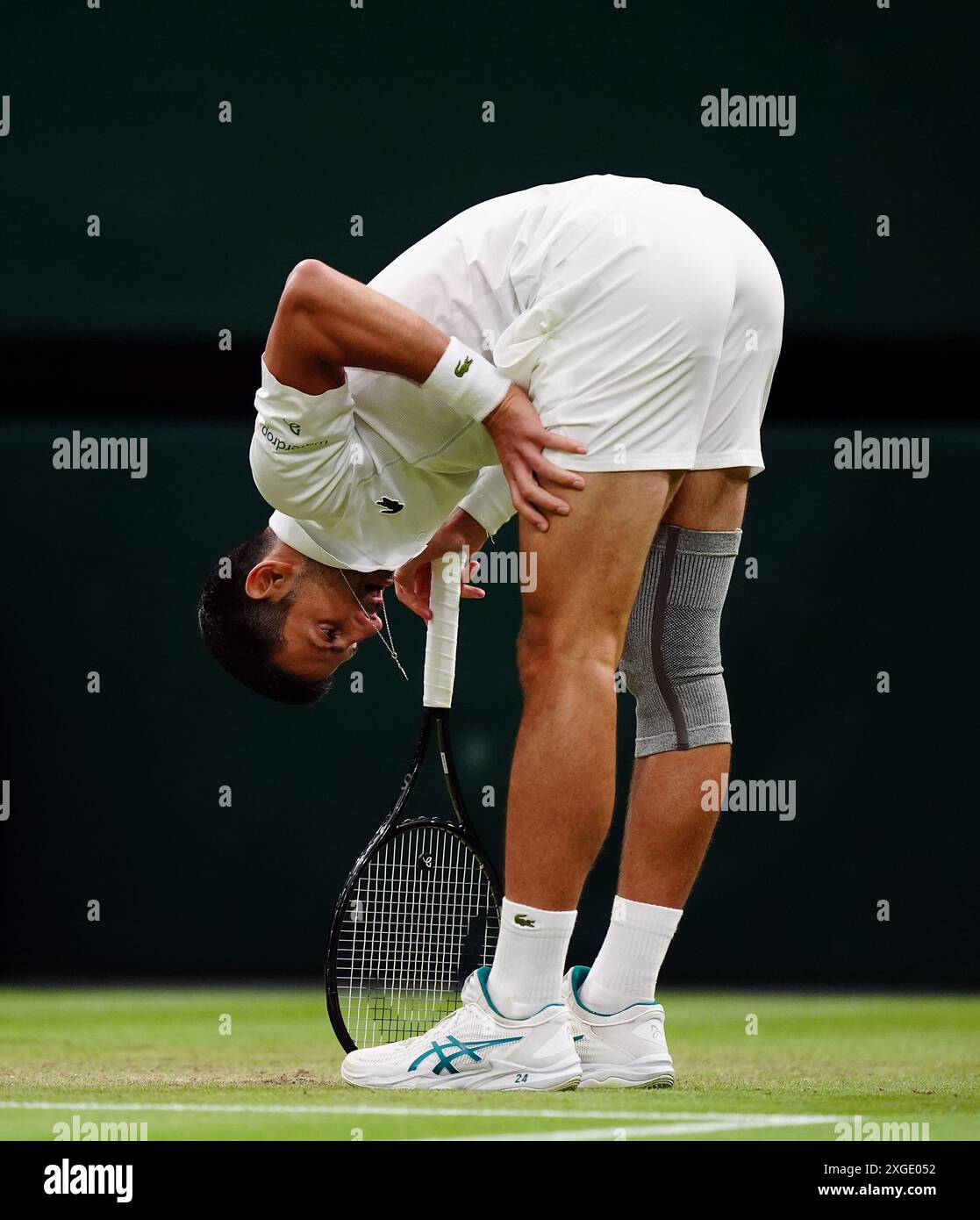Novak Djokovic stretches after falling over during his match against ...