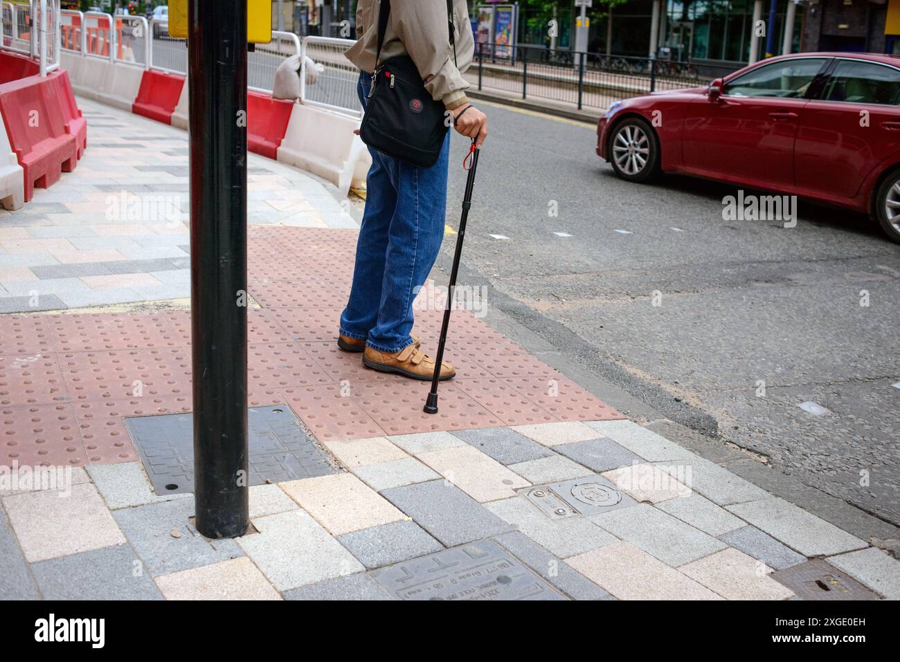 Pedestrian with walking stick about to cross urban road in ...