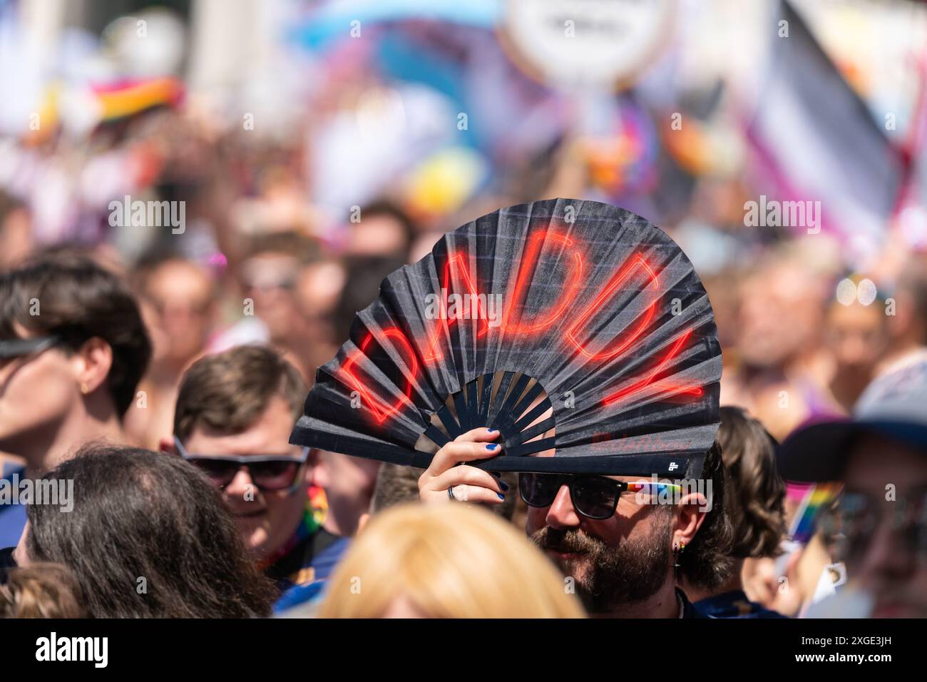 Festival goer at the London Pride parade holding a fan with the word ...