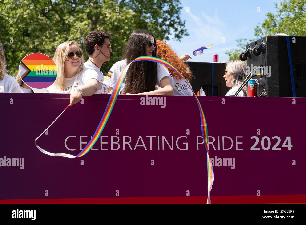 Person waving a rainbow ribbon on a Heathrow bus with a rainbow logo ...