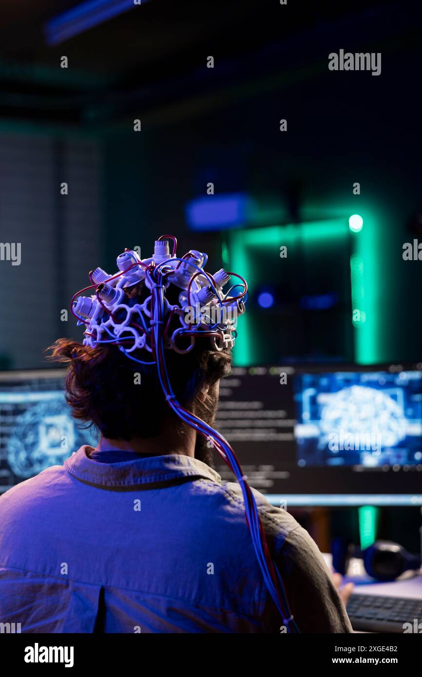 Engineer with EEG headset on programming brain transfer into computer virtual world, merging ...
