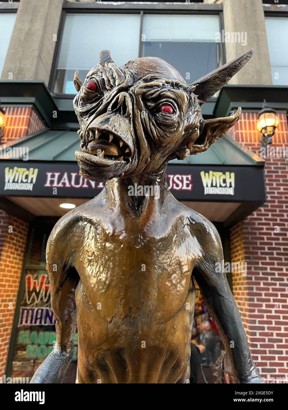 A scary monster and ghost stands outside the entrance to a haunted ...