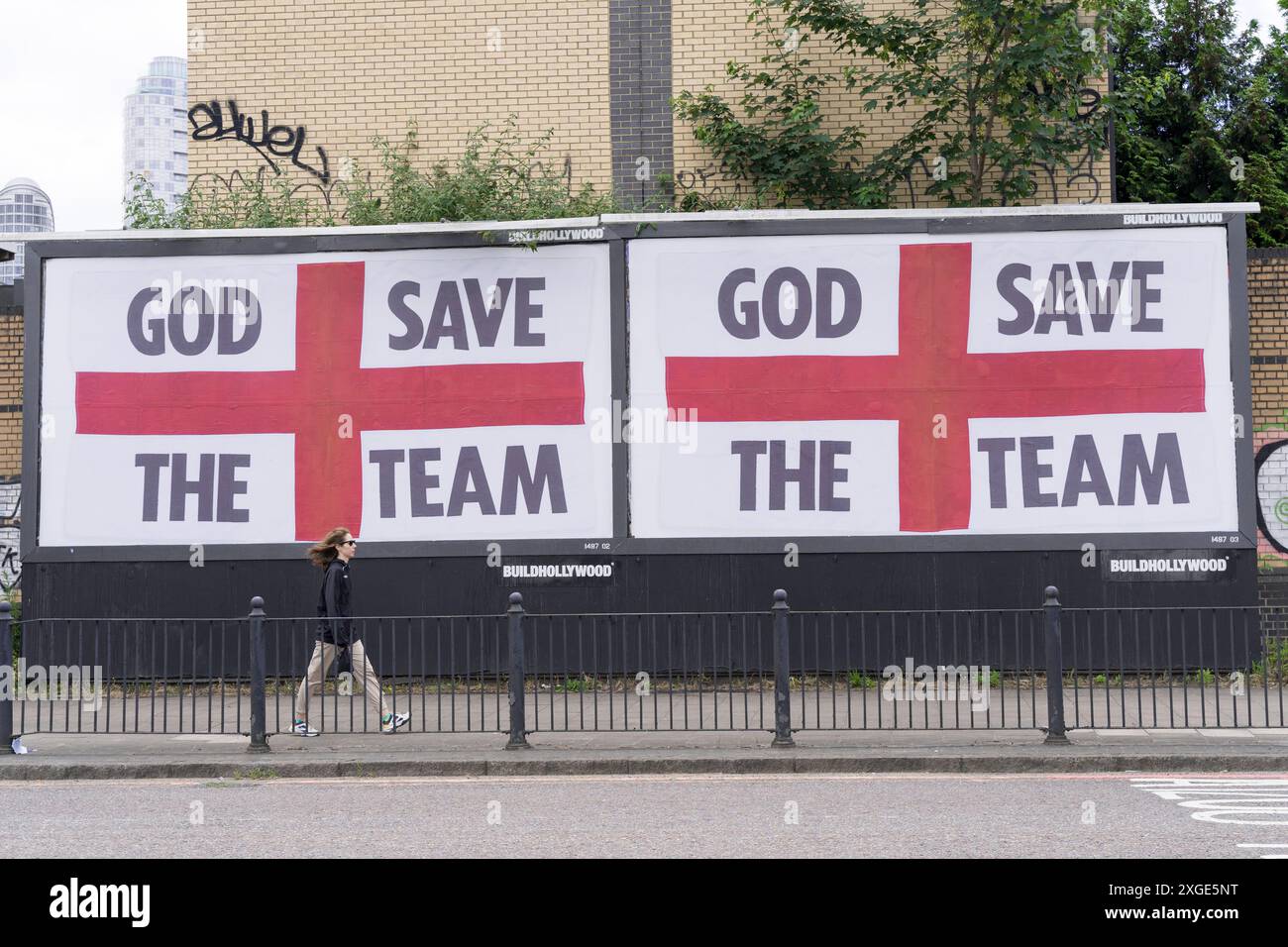 woman walk in front of a Billboard display , showing "God save the team ...