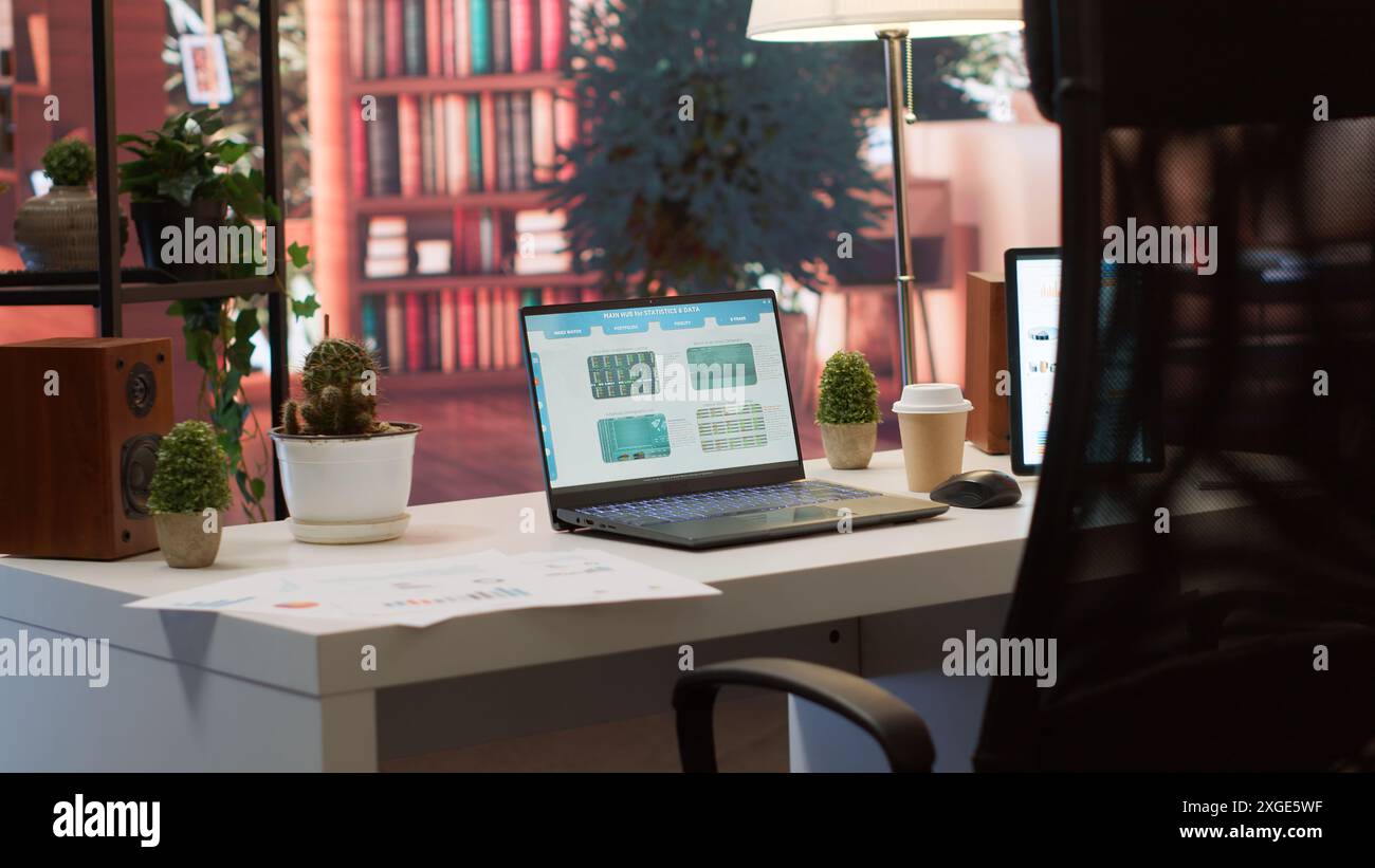 Empty home office setup showing documents and financial reports on laptop, desk used for a ...