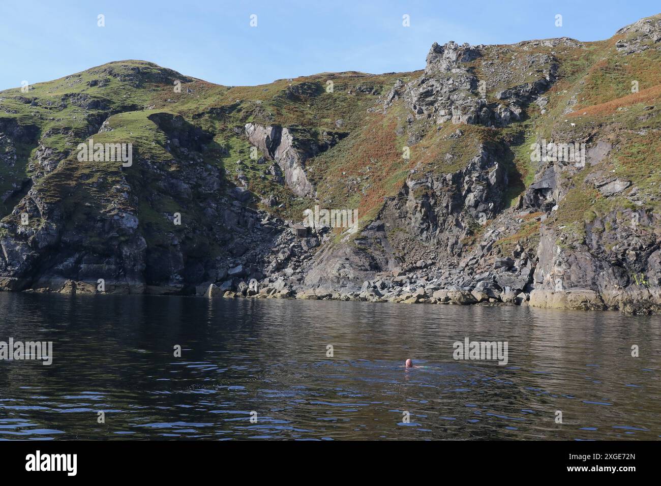Man swimming in sea below cliffs near Teelin Head County Donegal ...