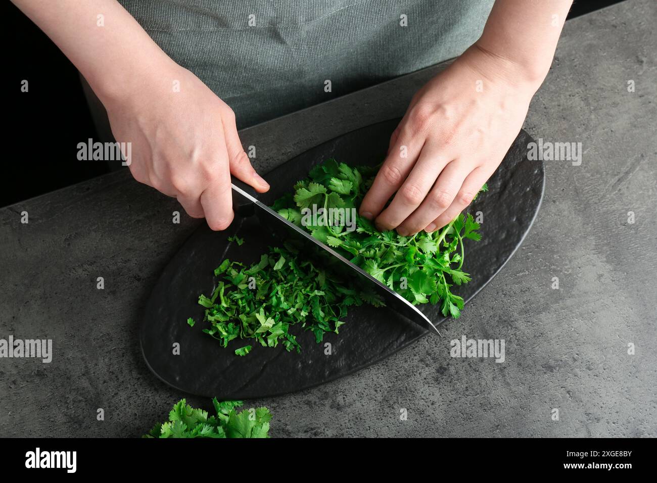 Woman cutting fresh coriander at grey textured table, top view Stock ...