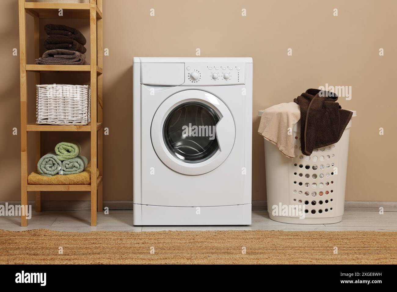 Washing machine, basket and shelving unit near beige wall indoors Stock ...