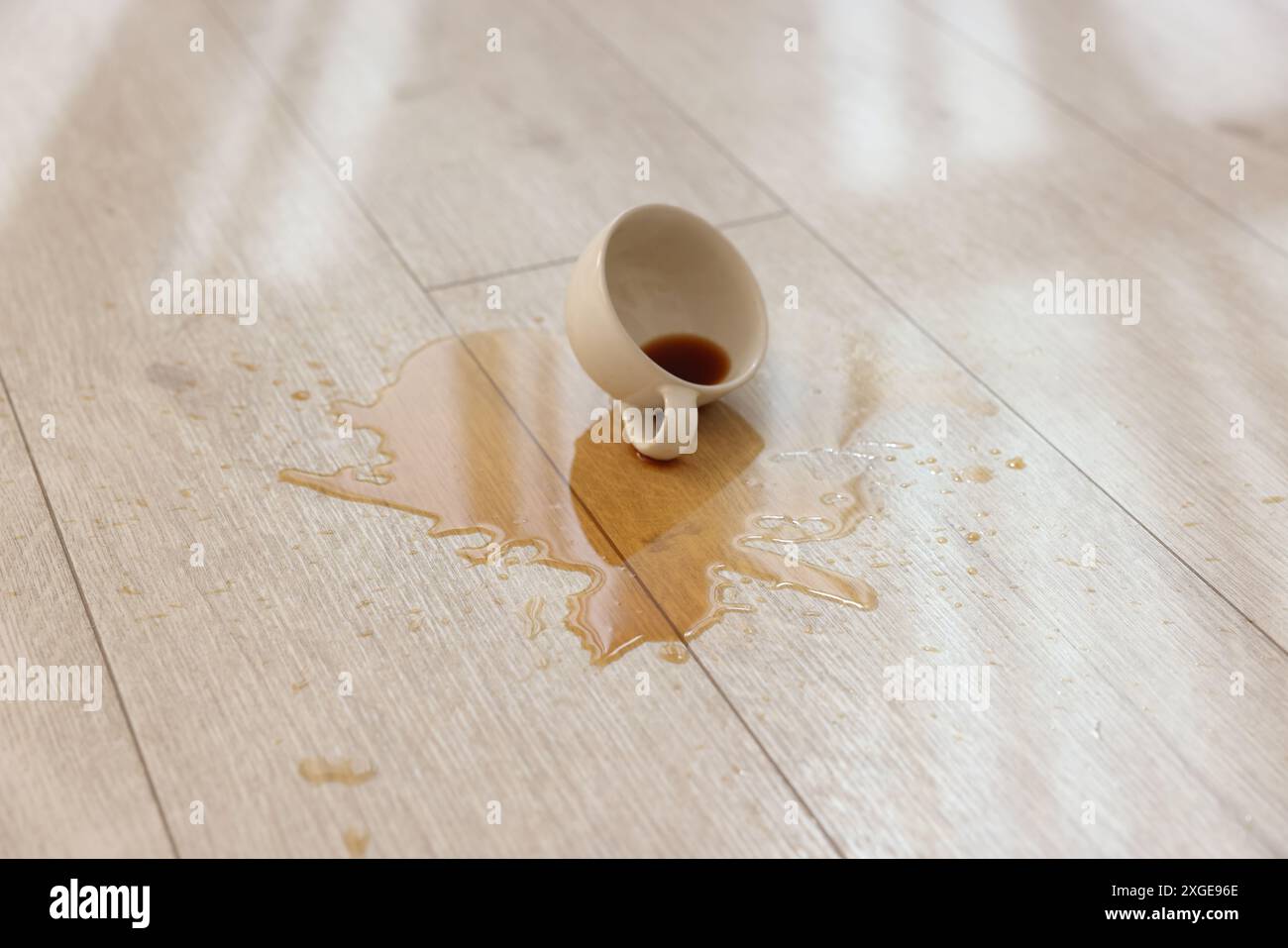 Cup with spilled drink on wooden floor Stock Photo - Alamy