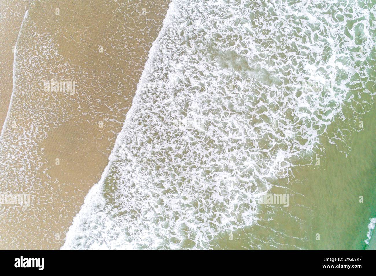 waves on the shore of a beach in the summer, aerial top view with drone ...