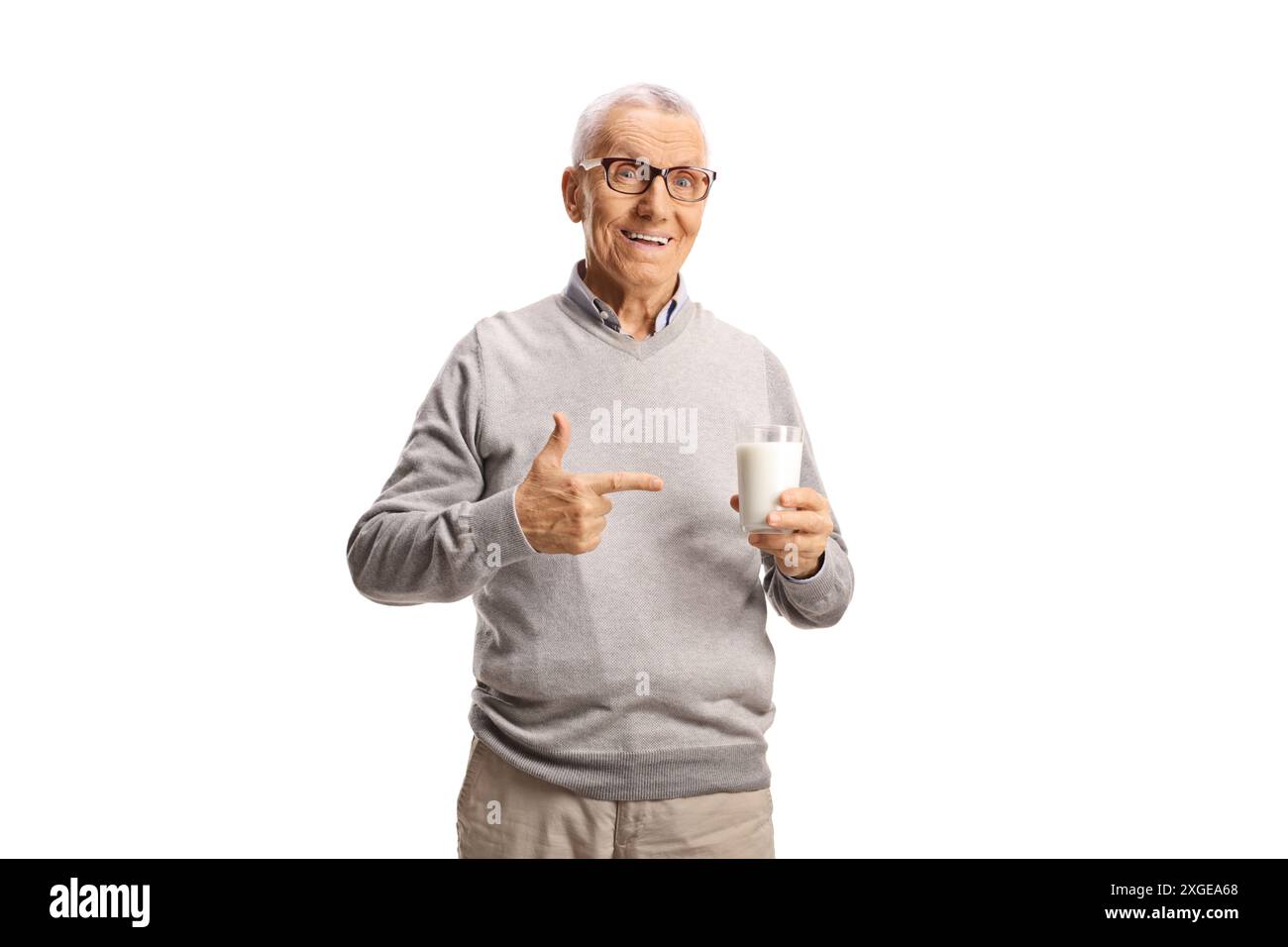 Elderly man pointing at a glass of milk isolated on white background ...