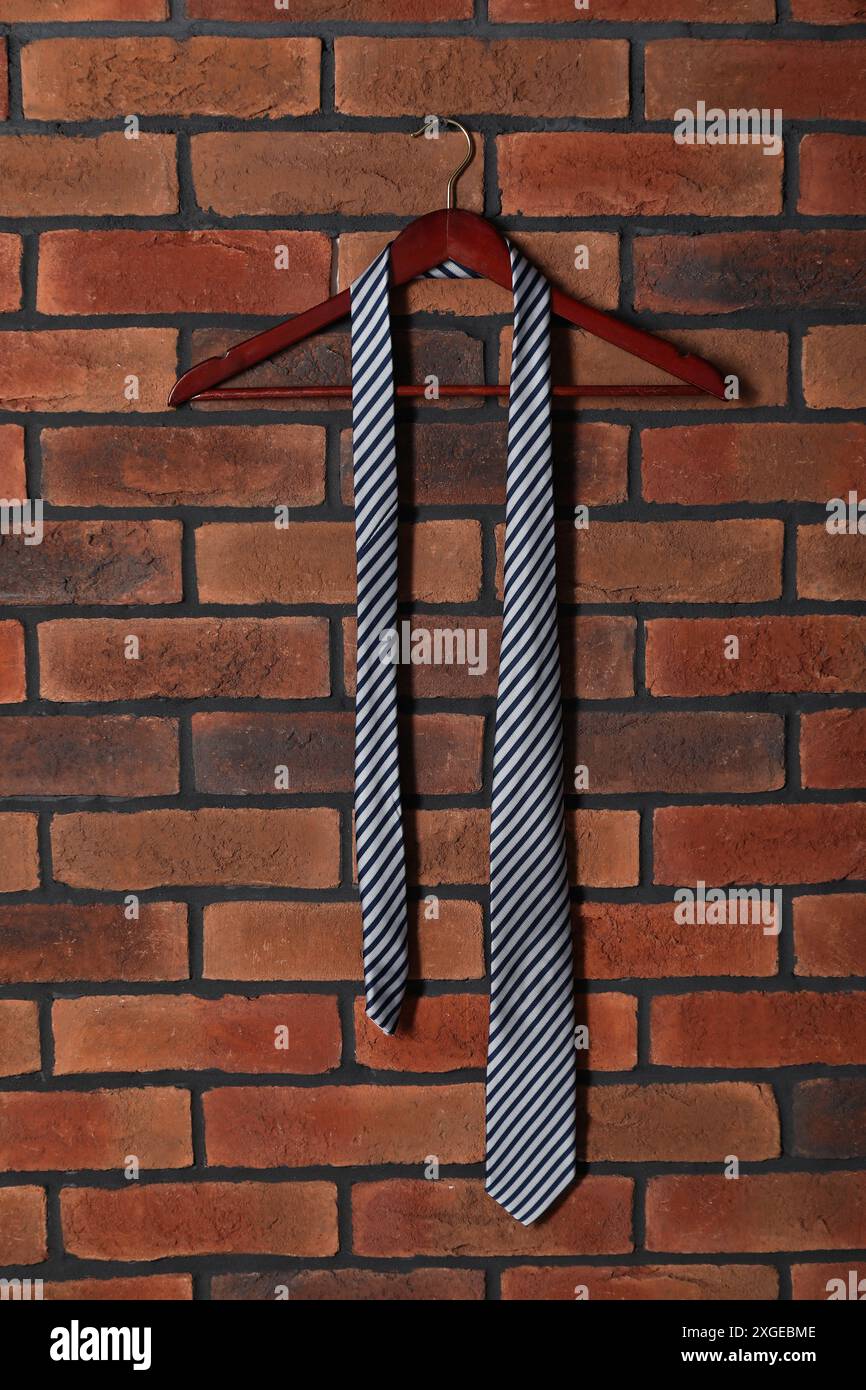 Hanger with striped necktie on red brick wall Stock Photo - Alamy