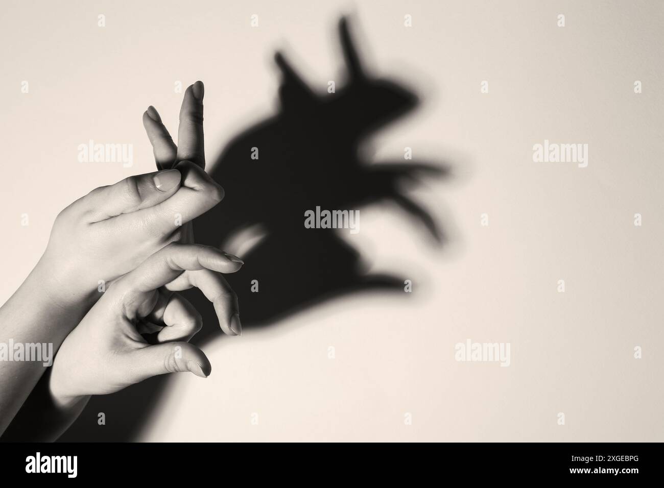 Shadow puppet. Woman making hand gesture like rabbit on light ...