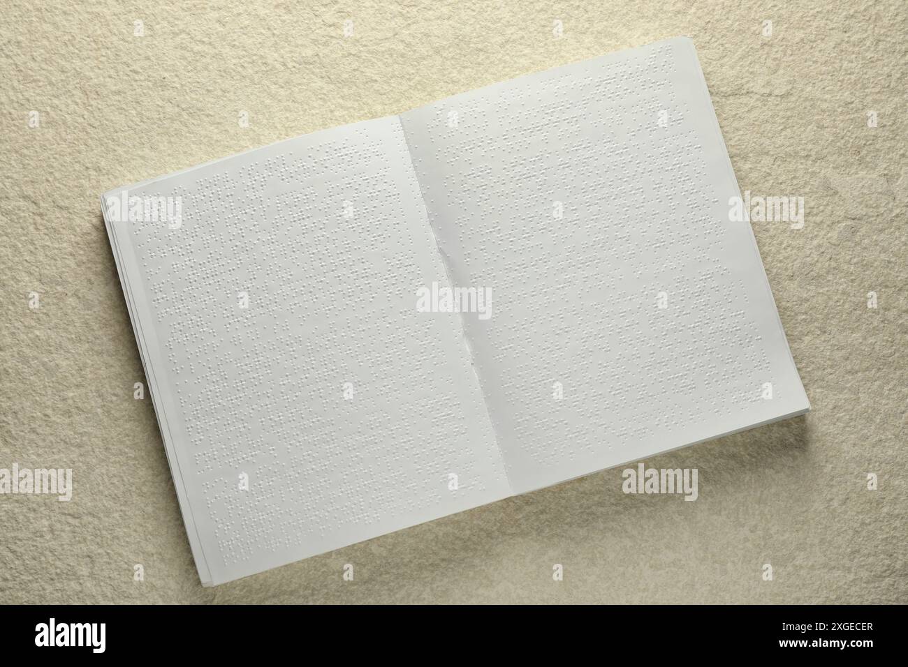 Book with Braille text on beige textured table, top view. Education and ...