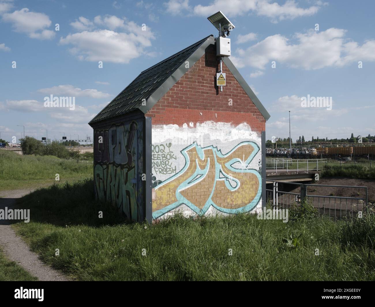 utility building decorated with graffiti next to the river Tame ...
