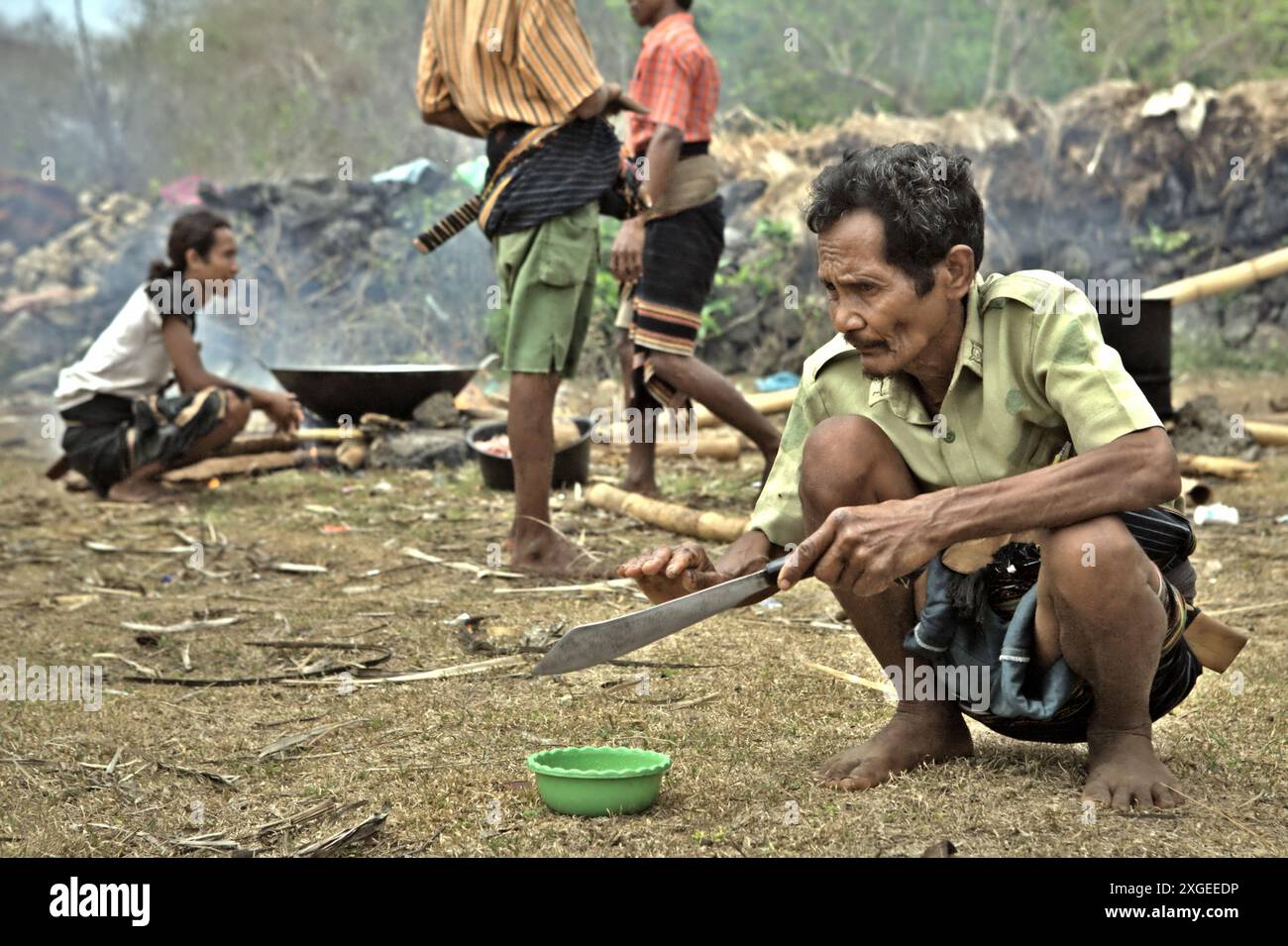 A man cleans his machete after giving a hand in meat slicing during the ...