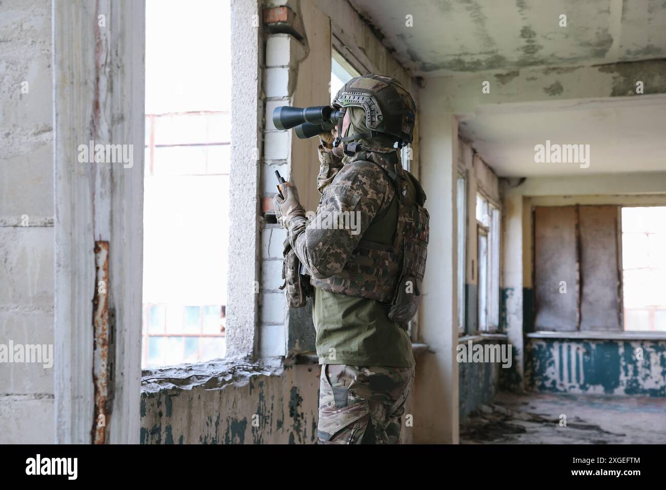 Military mission. Soldier in uniform with binoculars inside abandoned ...
