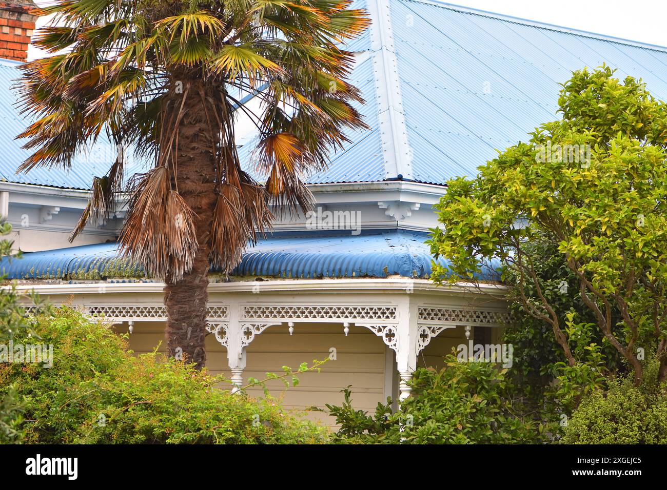Classic white wooden villa with blue corrugated metal roof and ...