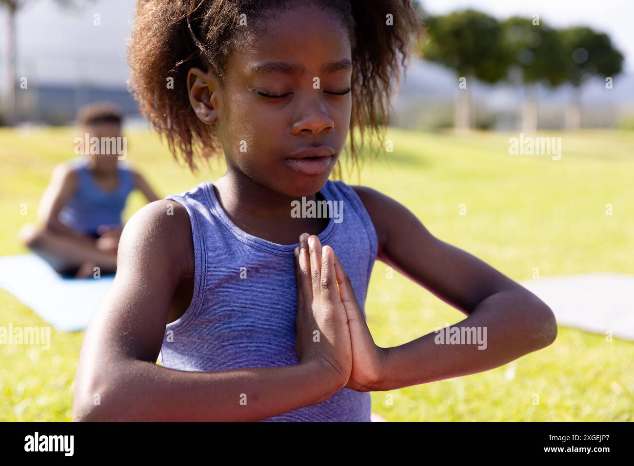 Happy african american schoolchildren doing yoga and meditating on ...