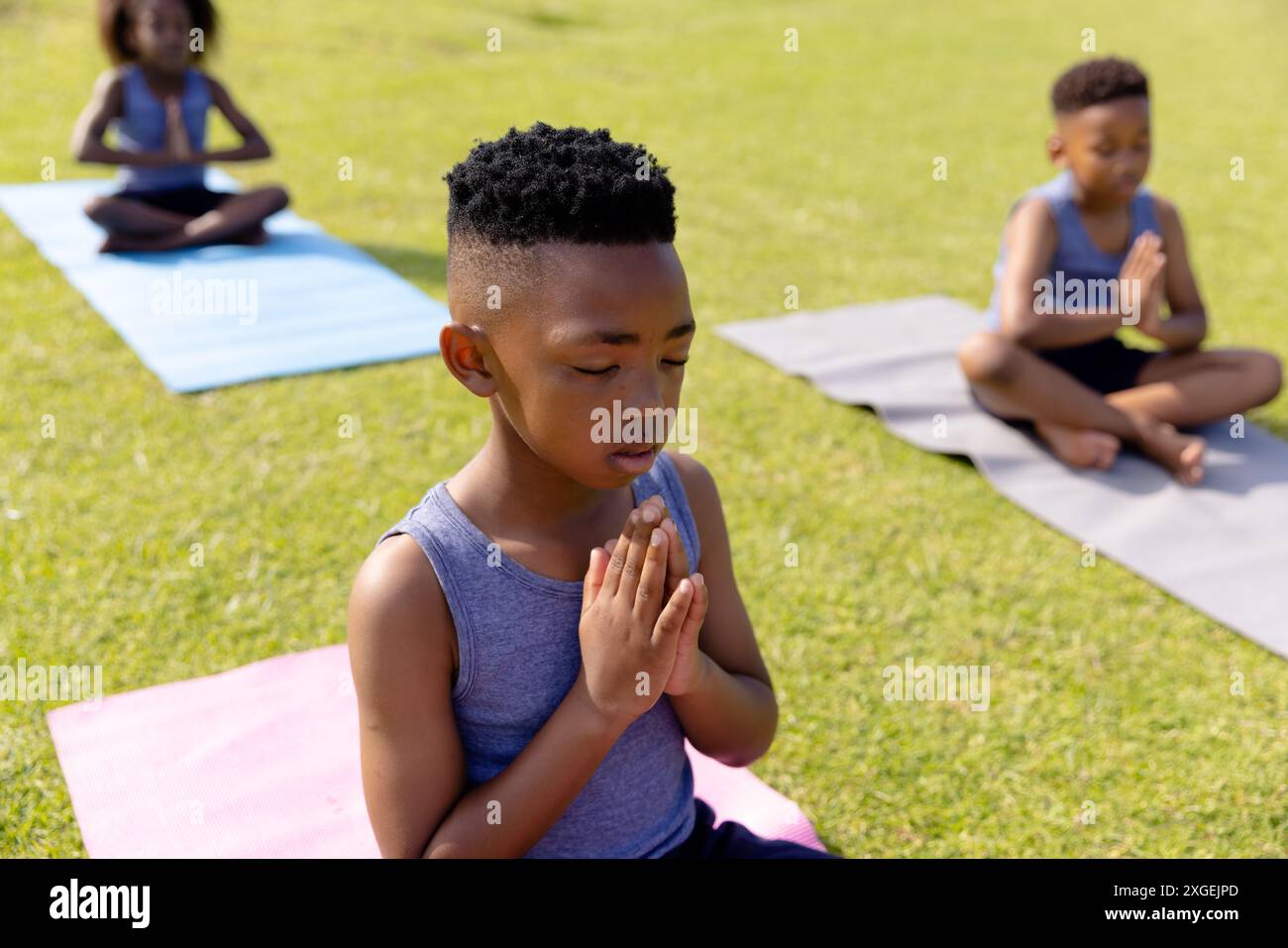 Happy african american schoolchildren doing yoga and meditating on ...