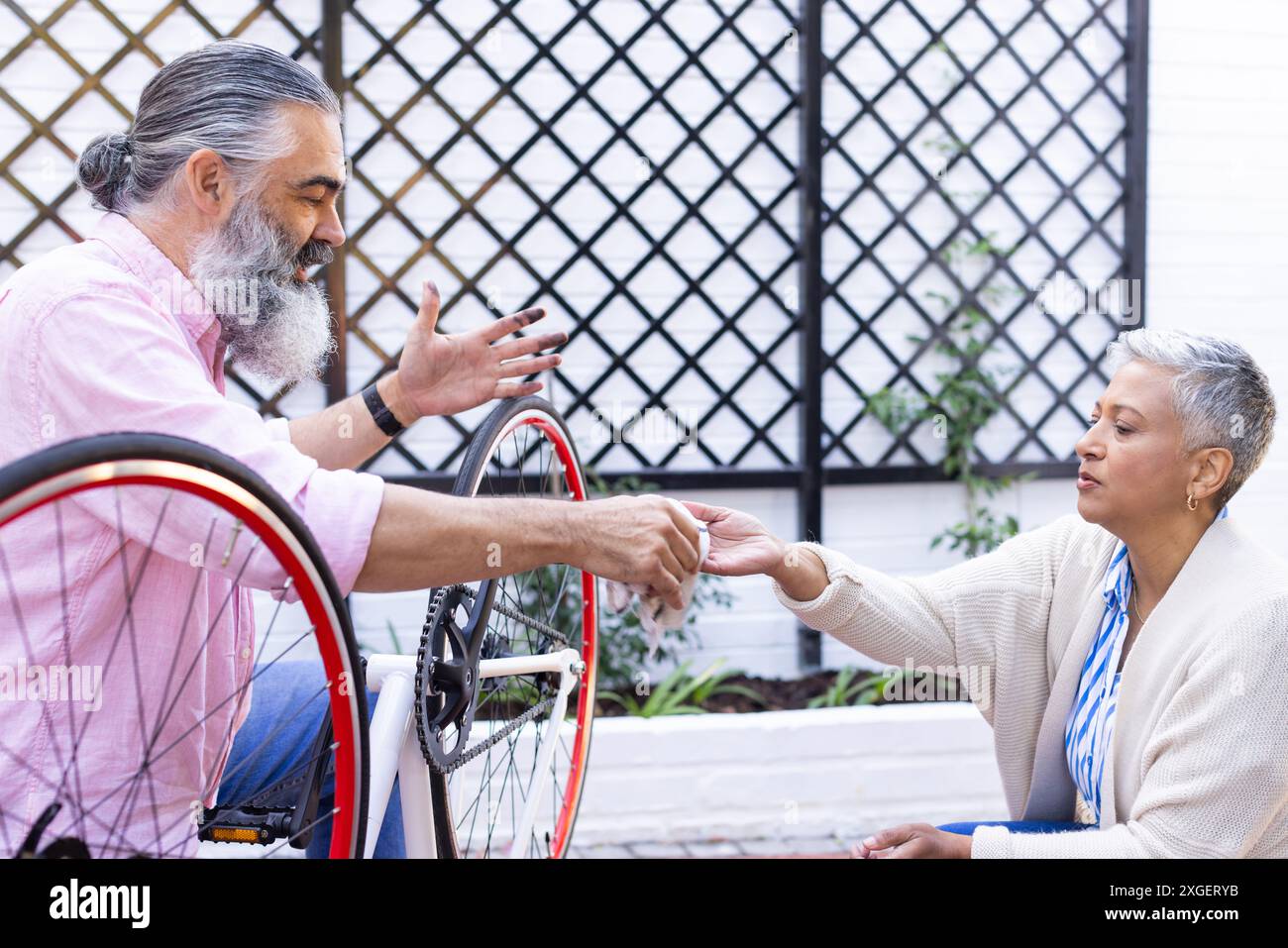 Repairing bicycle, senior couple sharing tools while working together ...
