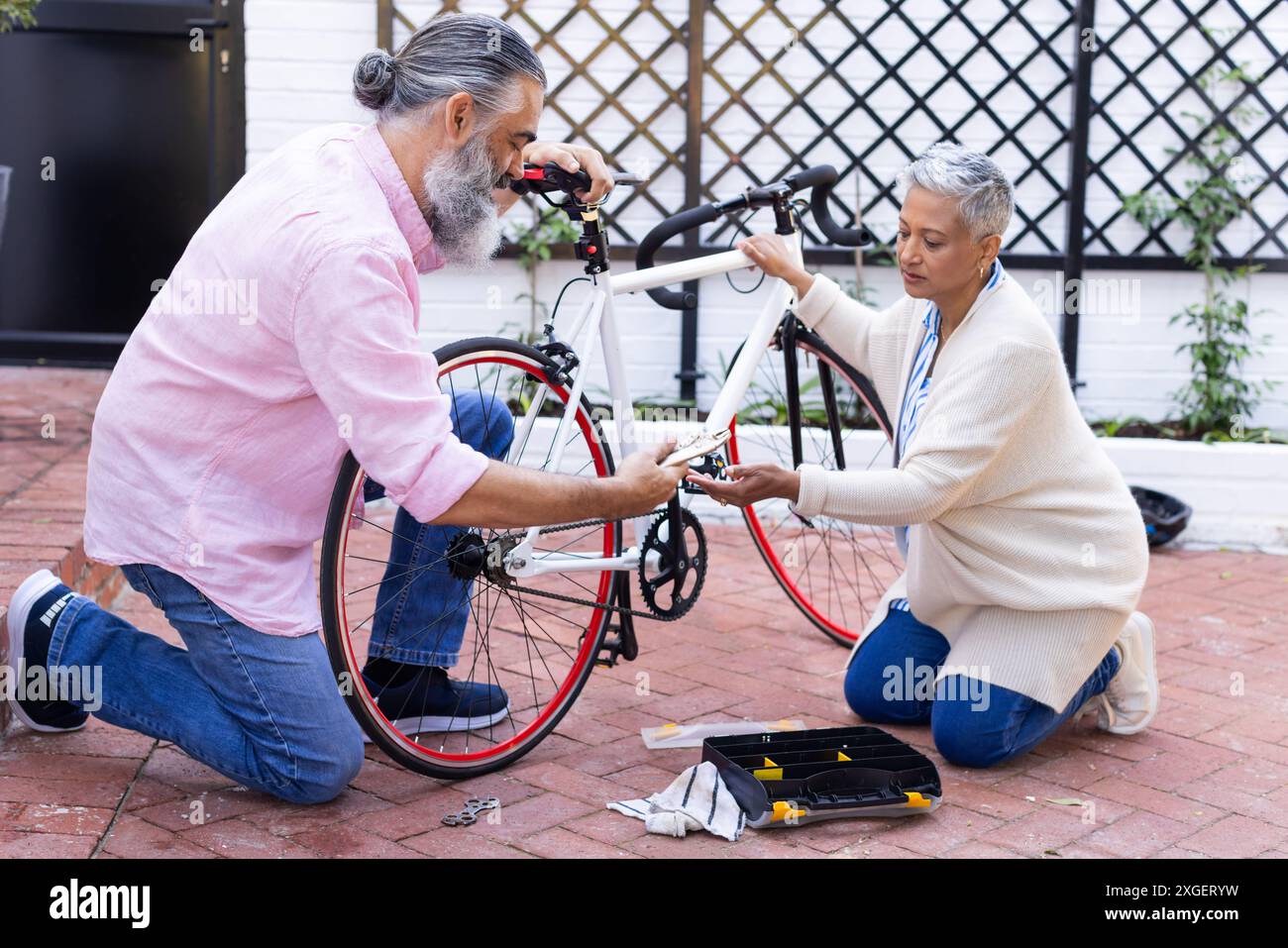 Repairing bicycle together, senior couple working with tools in ...