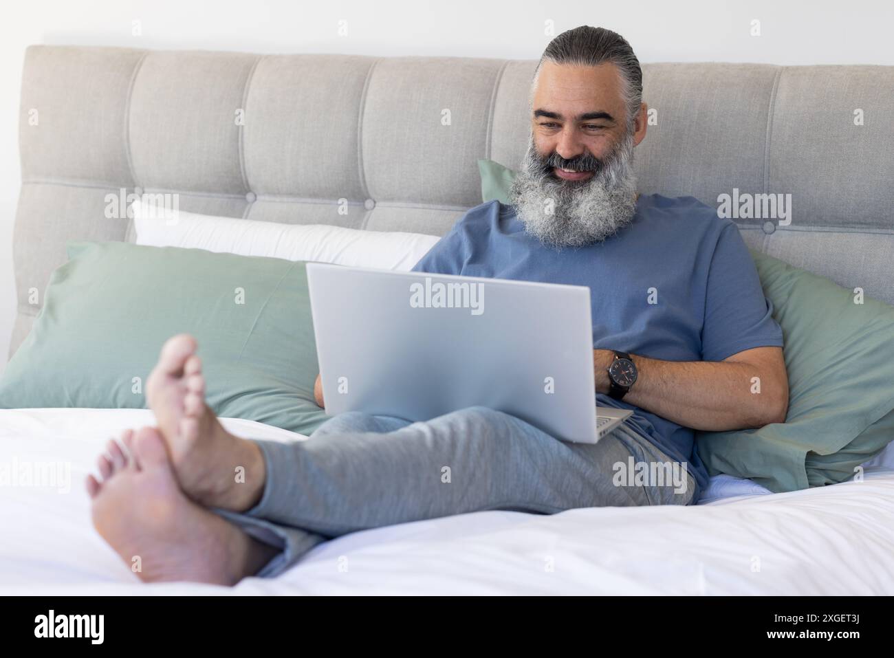 Working from home, senior man using laptop while sitting on bed Stock Photo - Alamy