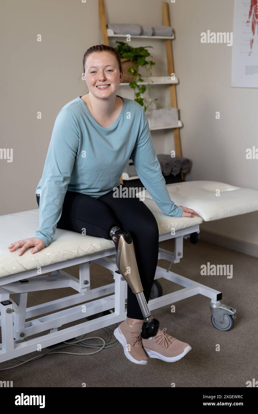 Smiling woman with prosthetic leg sitting on examination table in ...