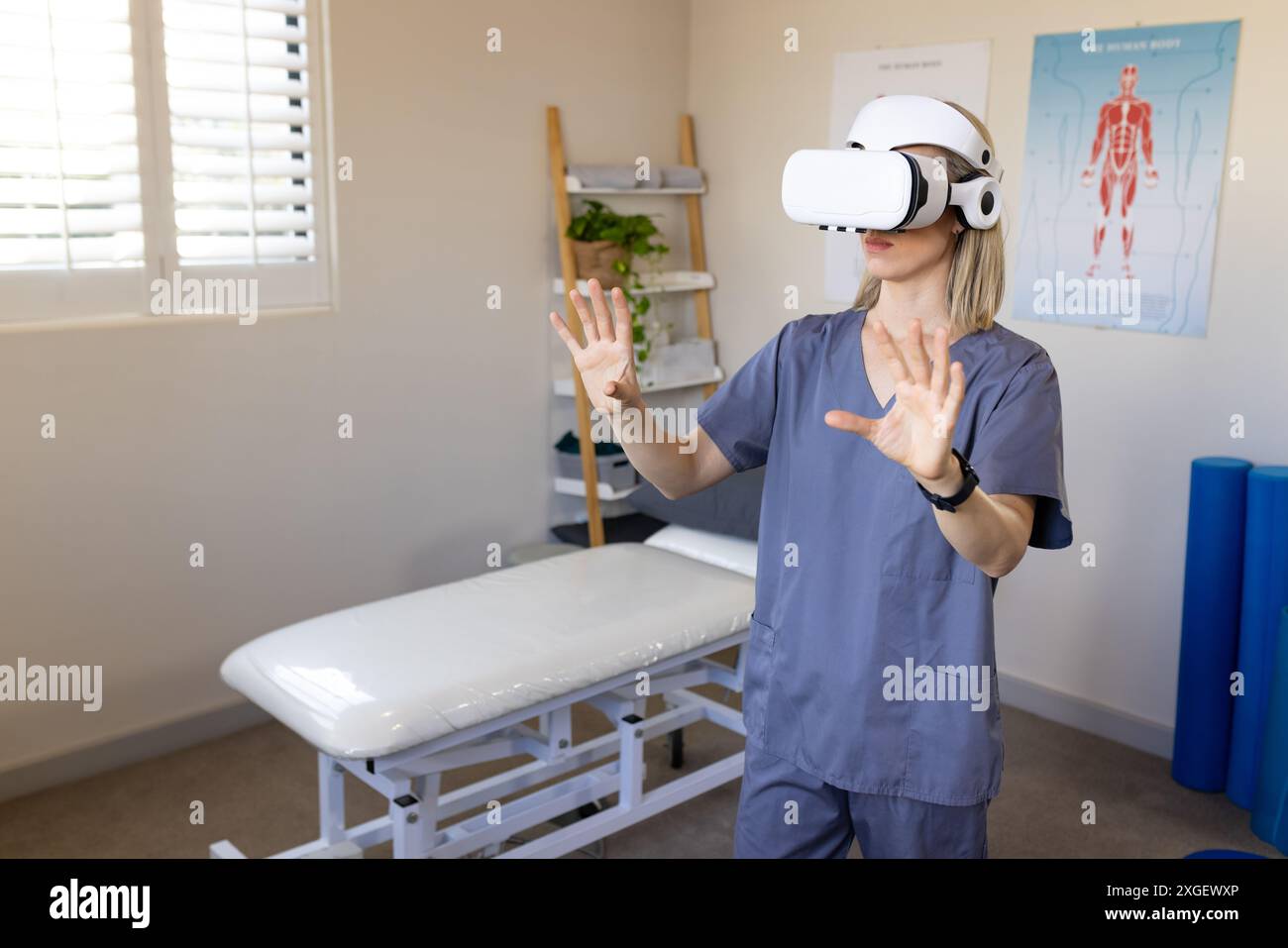 Wearing VR headset, medical professional in scrubs exploring virtual ...