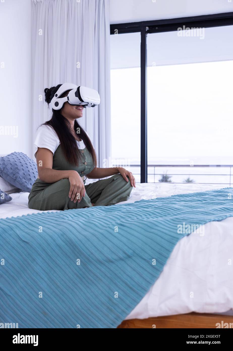 Using VR vr vr headset, woman sitting on bed in modern bedroom, copy space Stock Photo - Alamy