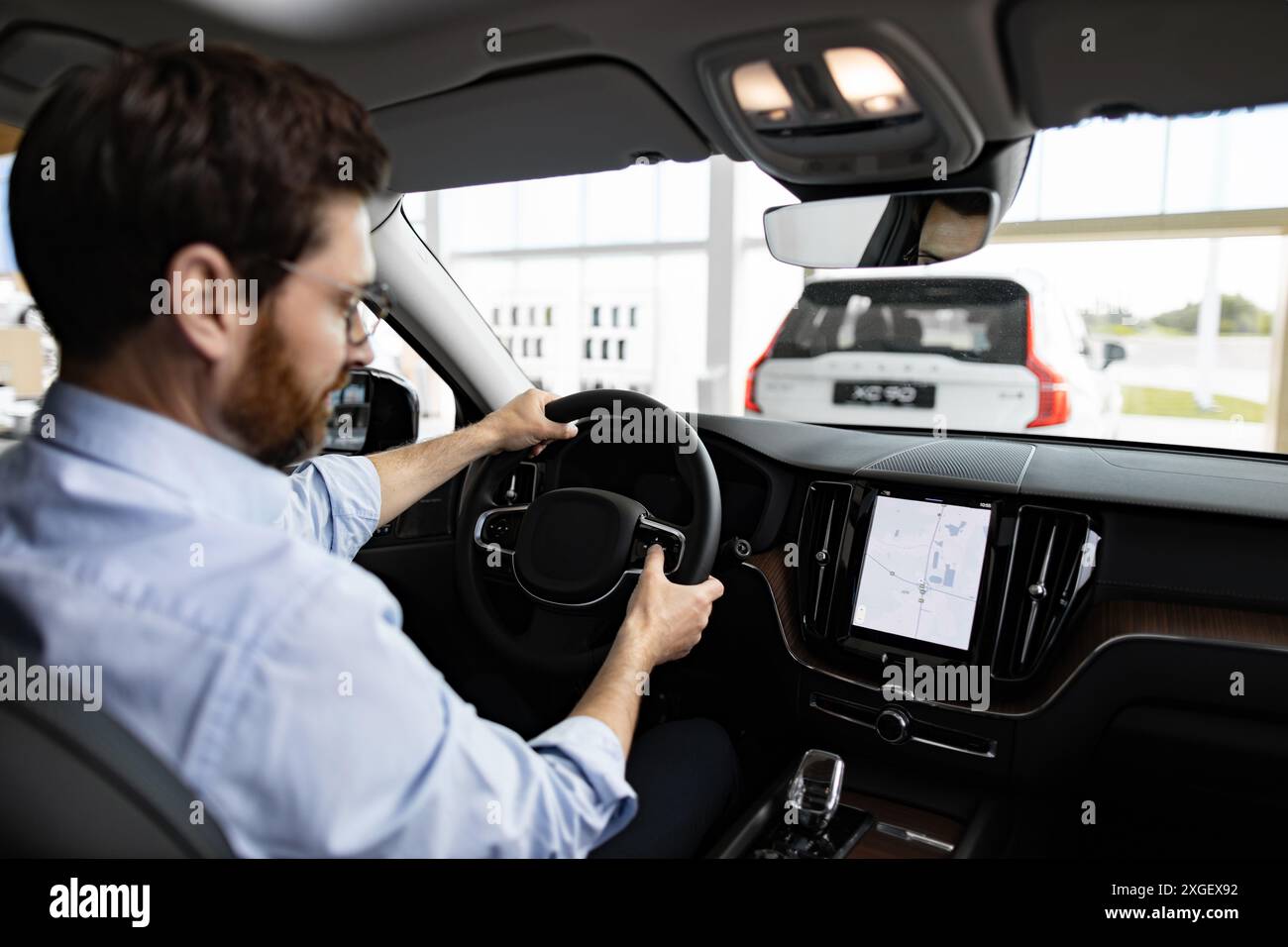 Businessman inside car dealership showroom test driving vehicle Stock ...