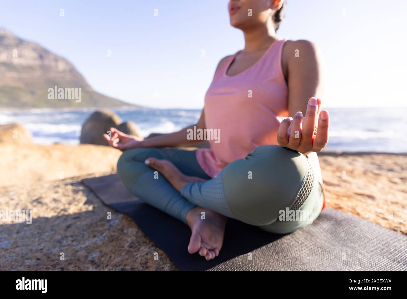 Meditating on yoga mat, woman practicing mindfulness by ocean outdoors ...