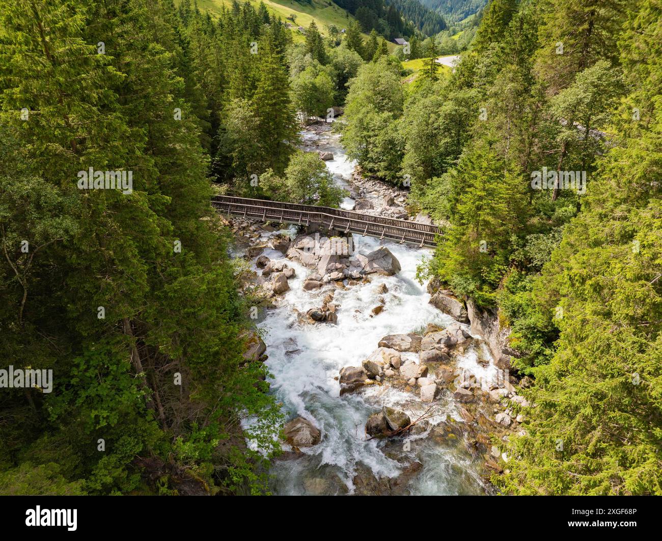 Wooden bridge over a fast-flowing river in a dense forest, Zillertal ...