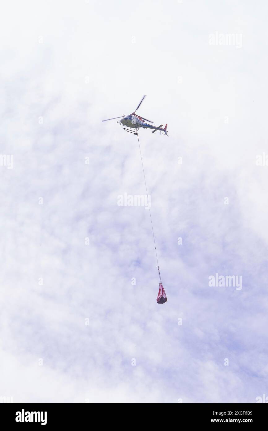 Helicopter flies in the sky and transports a load on a long rope, Klein ...