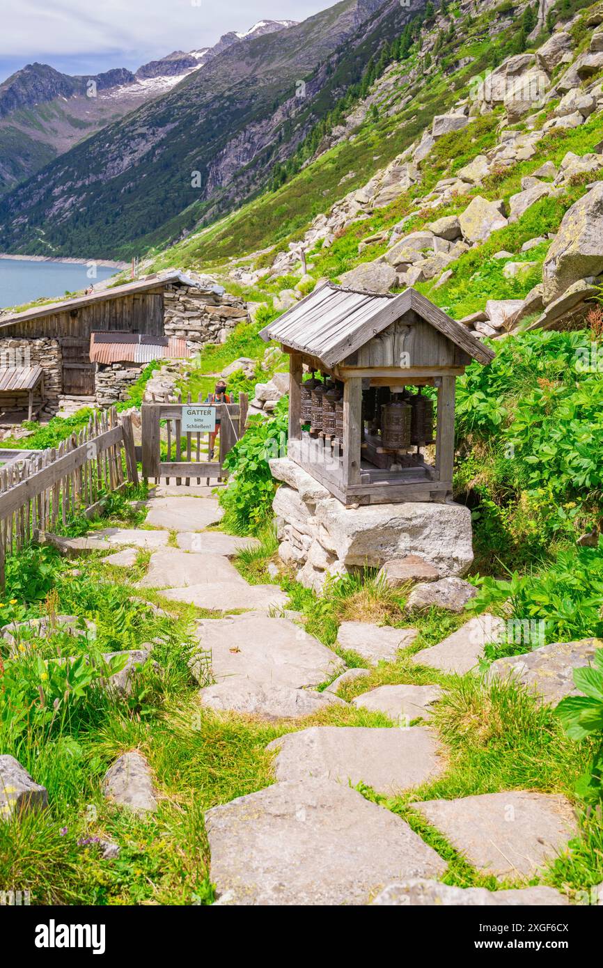 A picturesque mountain path leads to rustic wooden huts against an ... A picturesque mountain path leads to rustic wooden huts against an ...