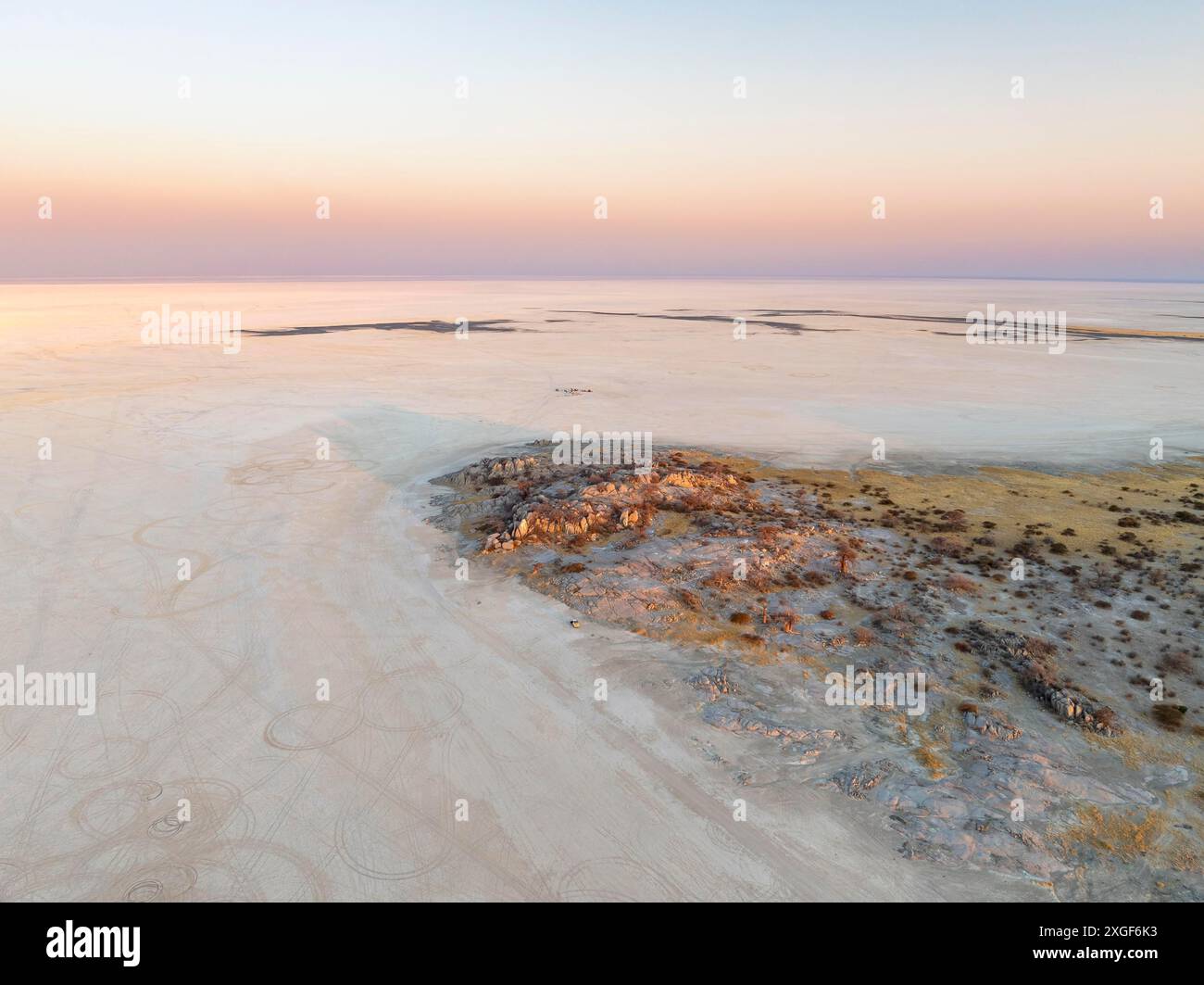 Rocky island with baobab trees in a dry salt pan, at sunset, aerial ...