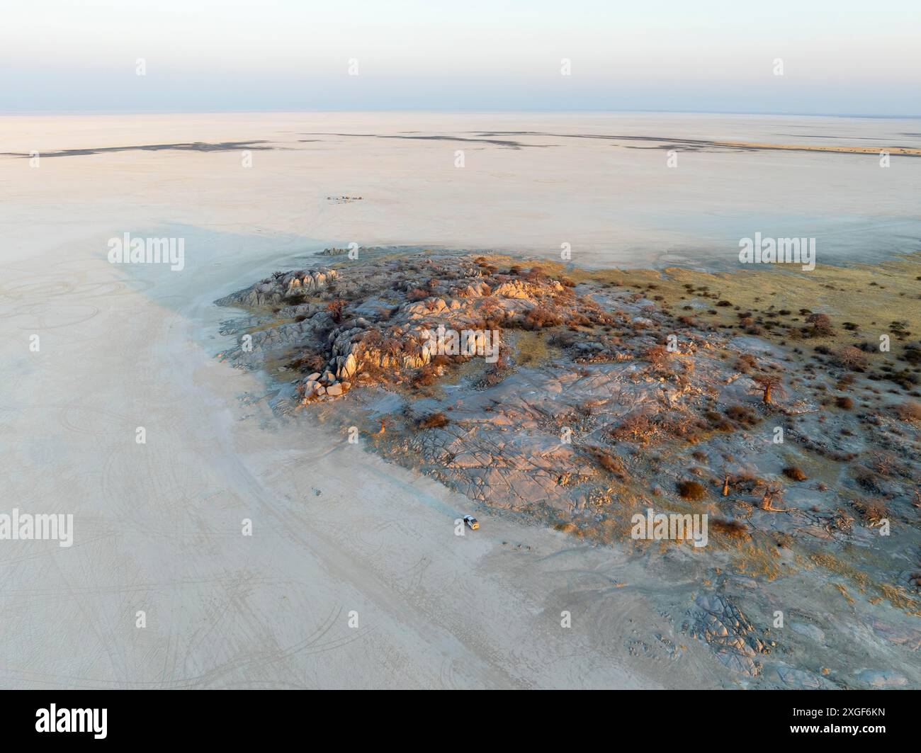 Rocky island with baobab trees in a dry salt pan, at sunset, off-road ...