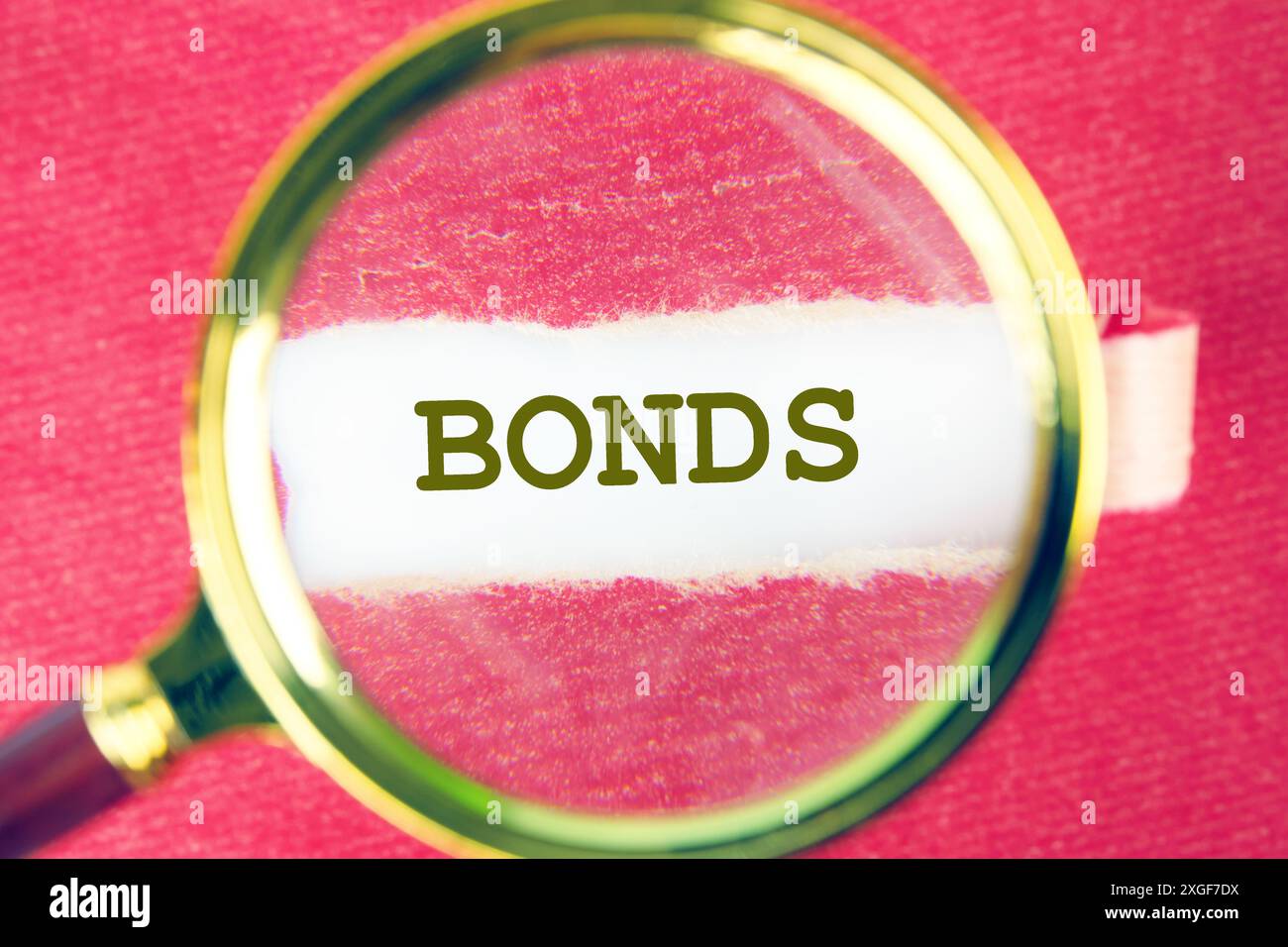 Business concept. BONDS word through a magnifying glass under torn ...