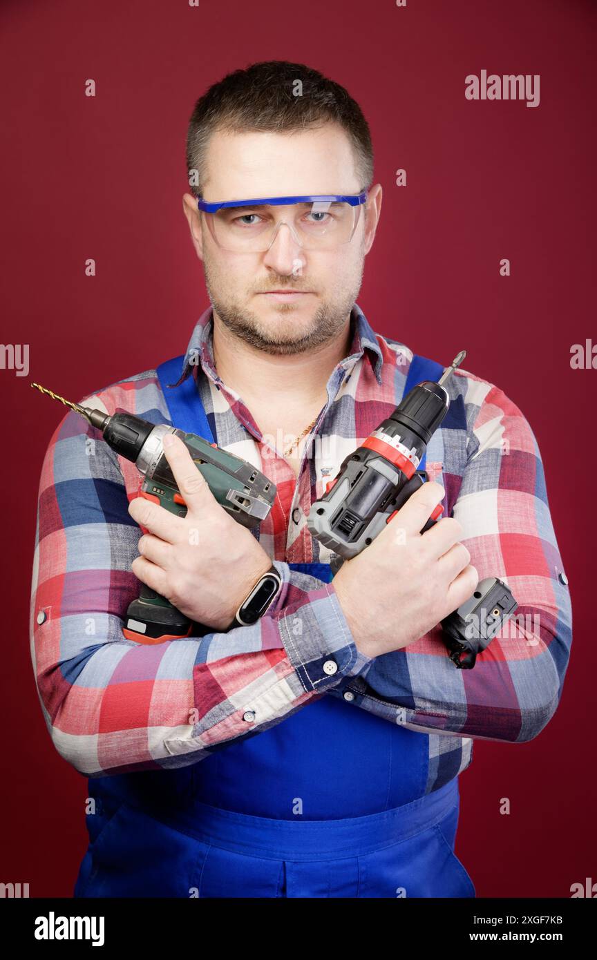 Serious Caucasian repairman in goggles holding woodworking tools ...