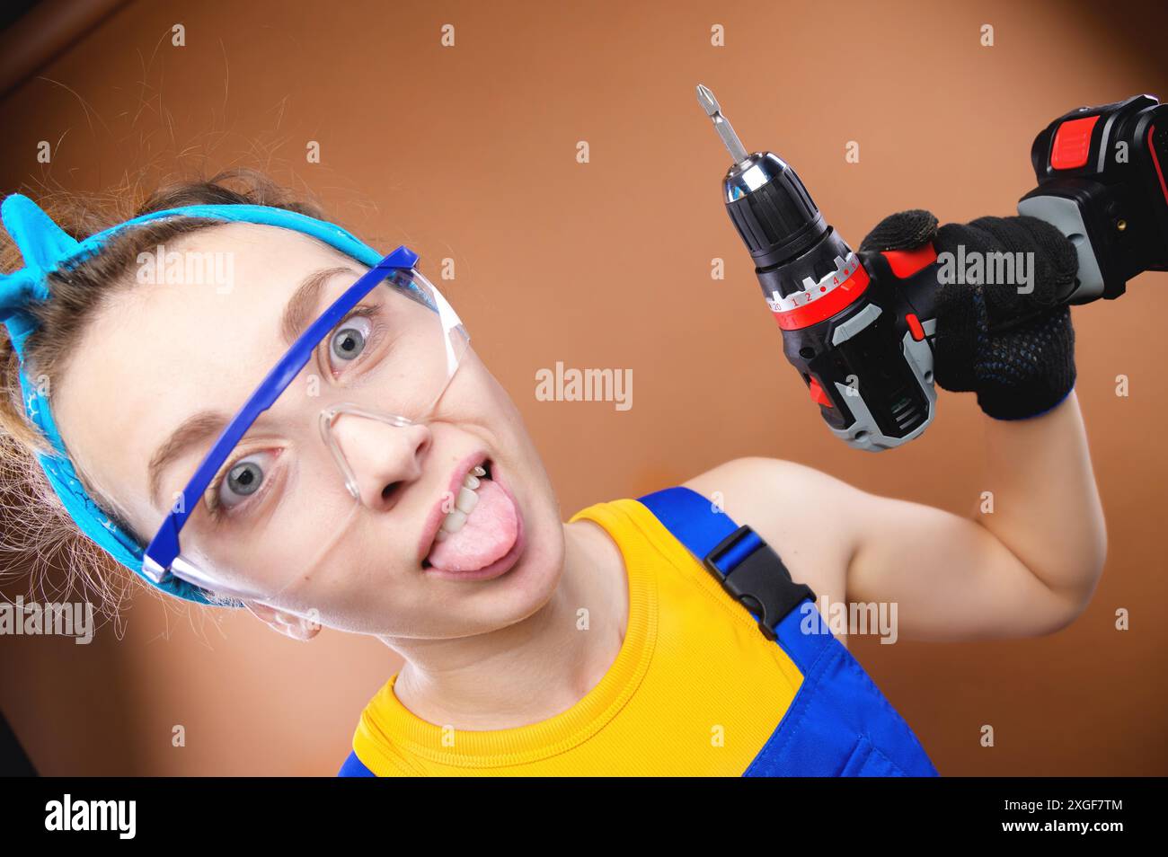Young crazy caucasian woman with a screwdriver in her hand shows her ...