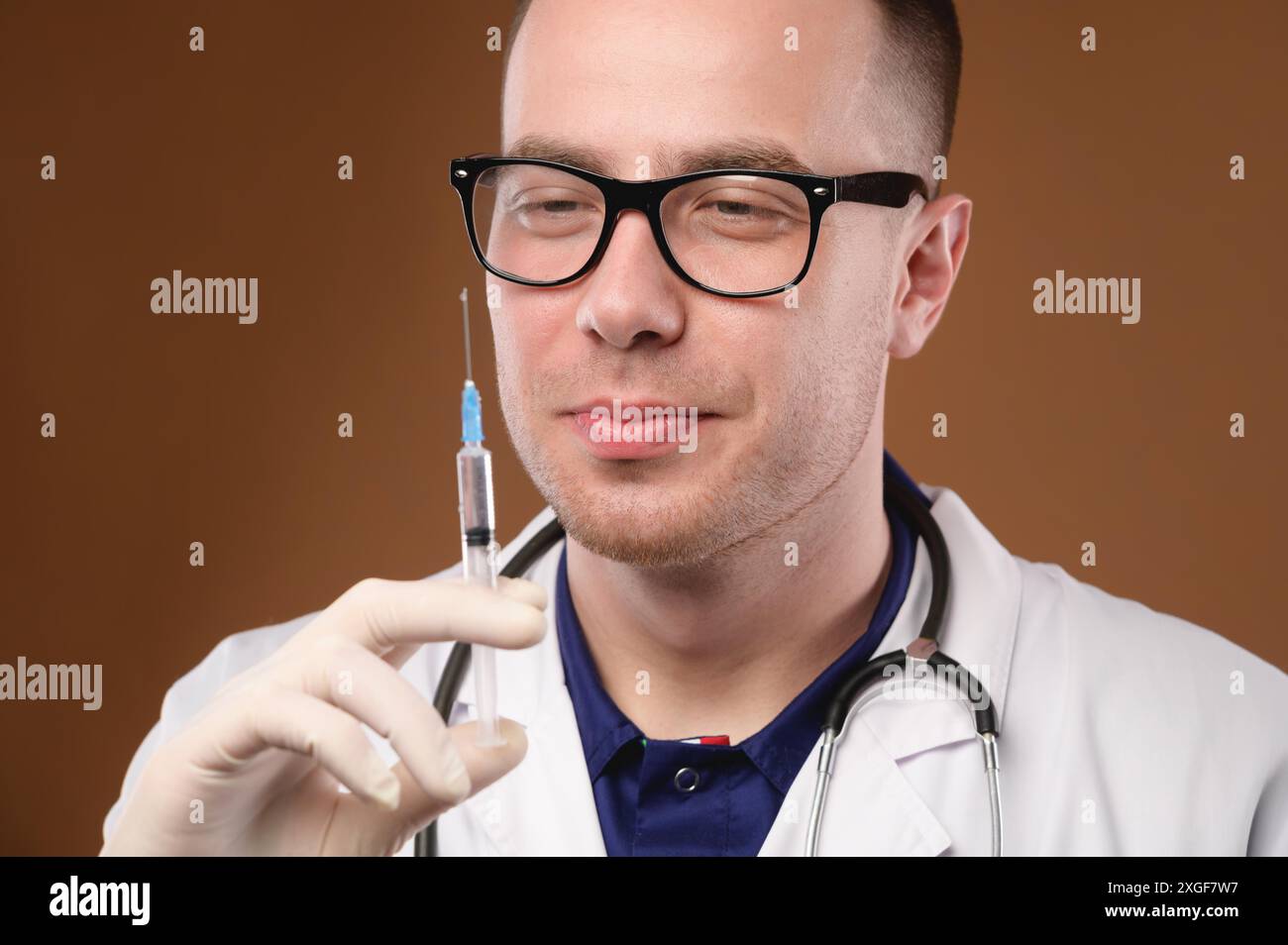 Handsome man in doctor uniform holding a syringe smiling happily, portrait studio shot Stock ...