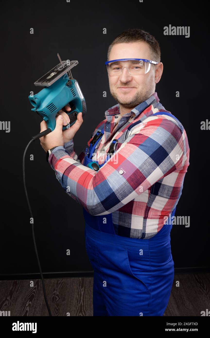 Caucasian repairman in goggles holding woodworking tools. Carpenter ...