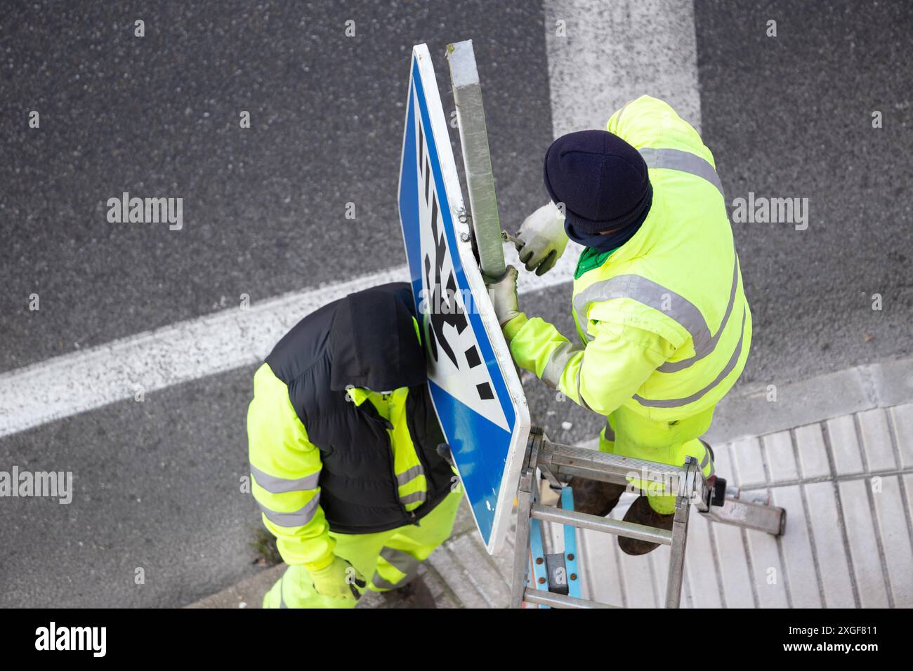 Workers changing a damaged road sign on street sidewalk. Public ...