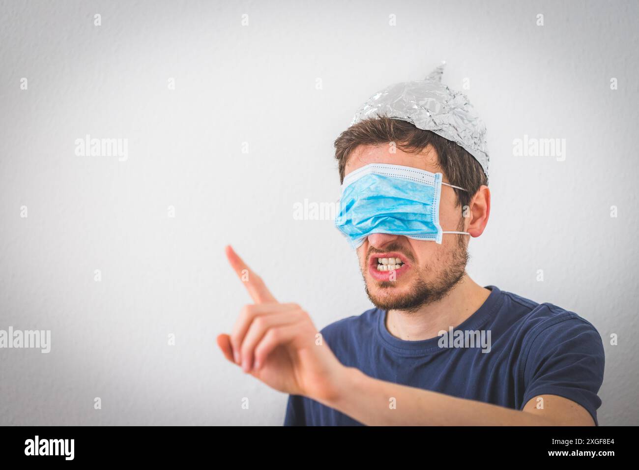 Young angry man with aluminum cap and face mask over the eyes is ...