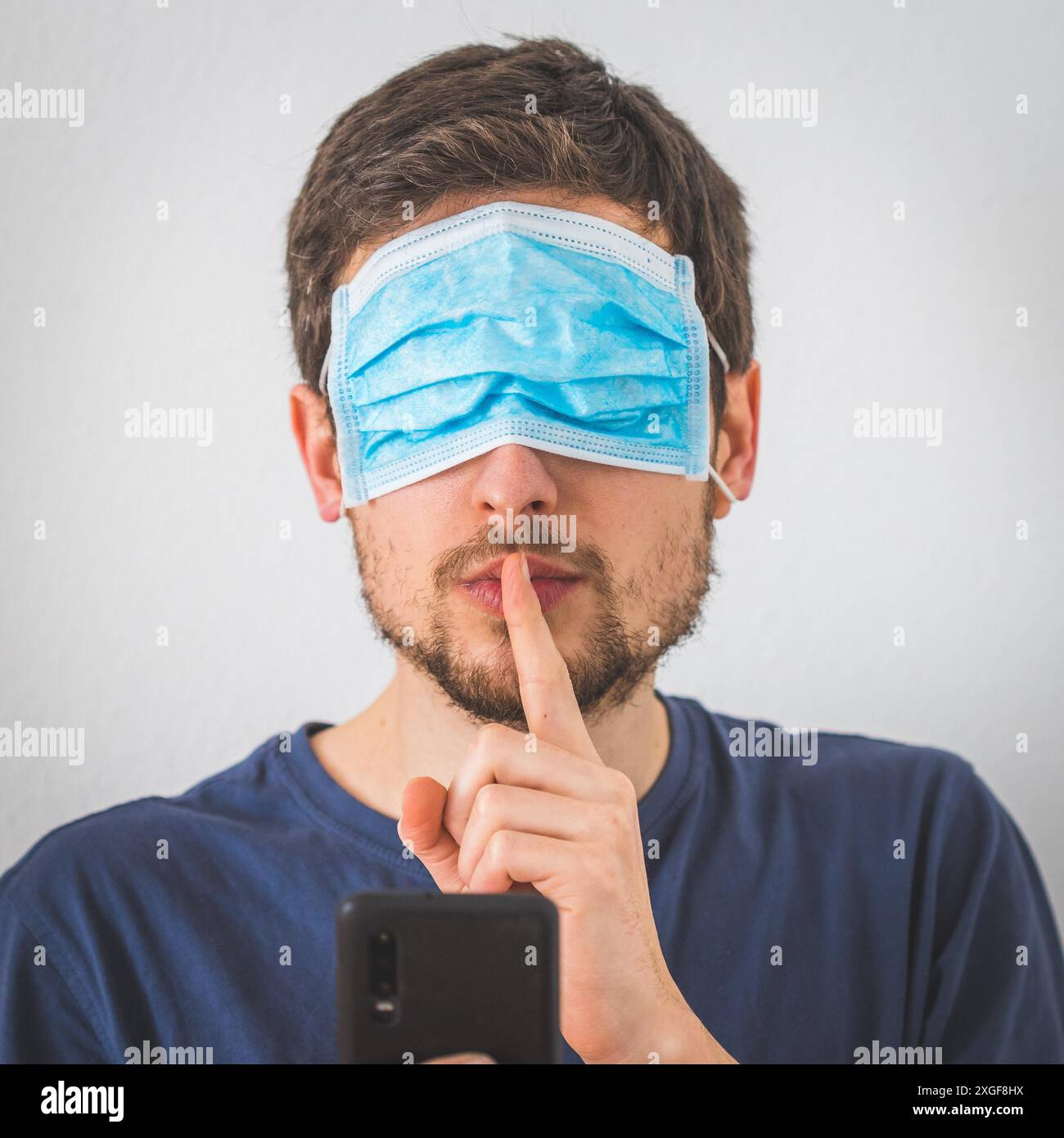 Young angry man with face mask over the eyes is doing a psst! gesture ...