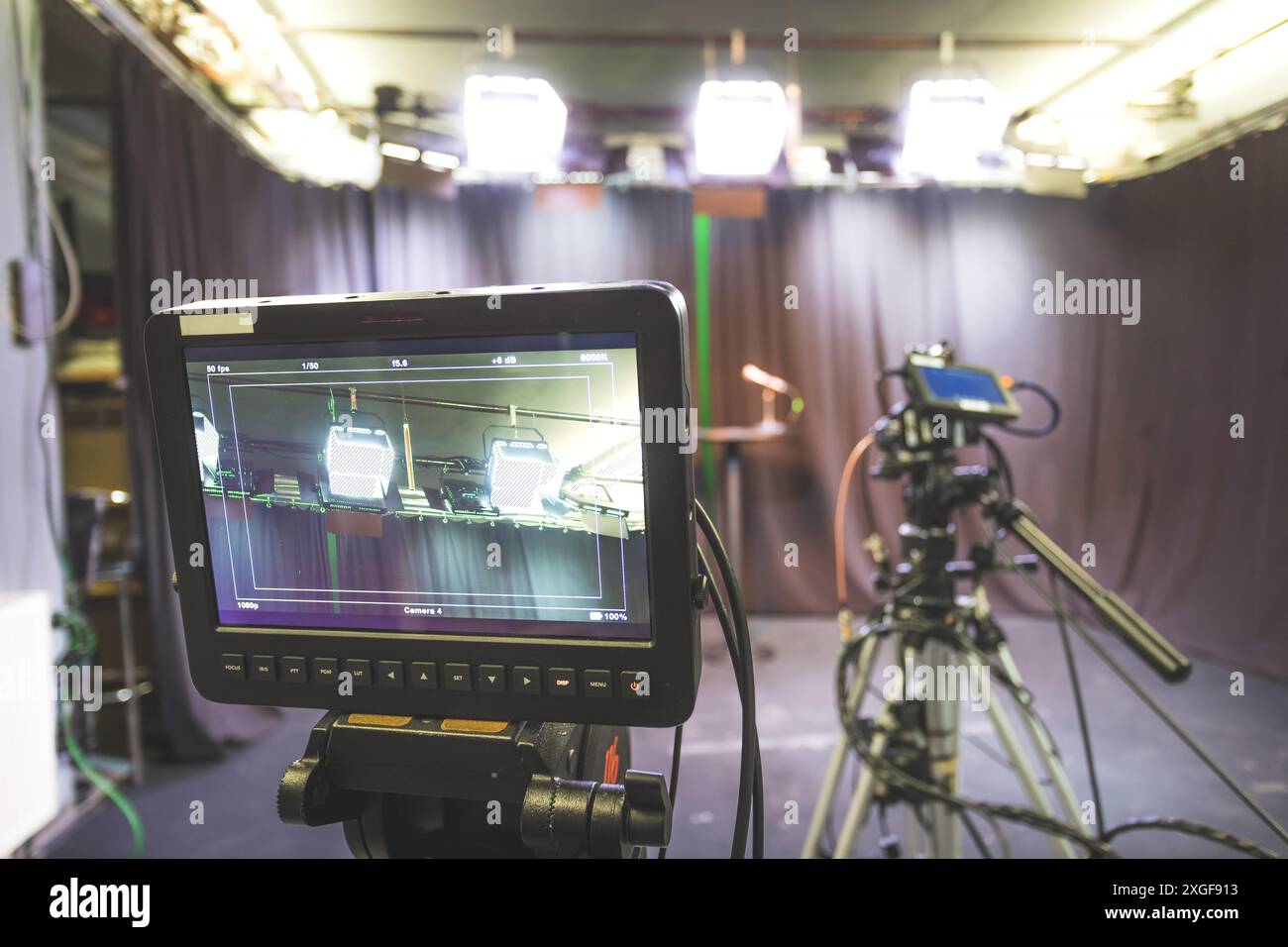 Film camera on a tripod in a television broadcasting studio, spotlights ...